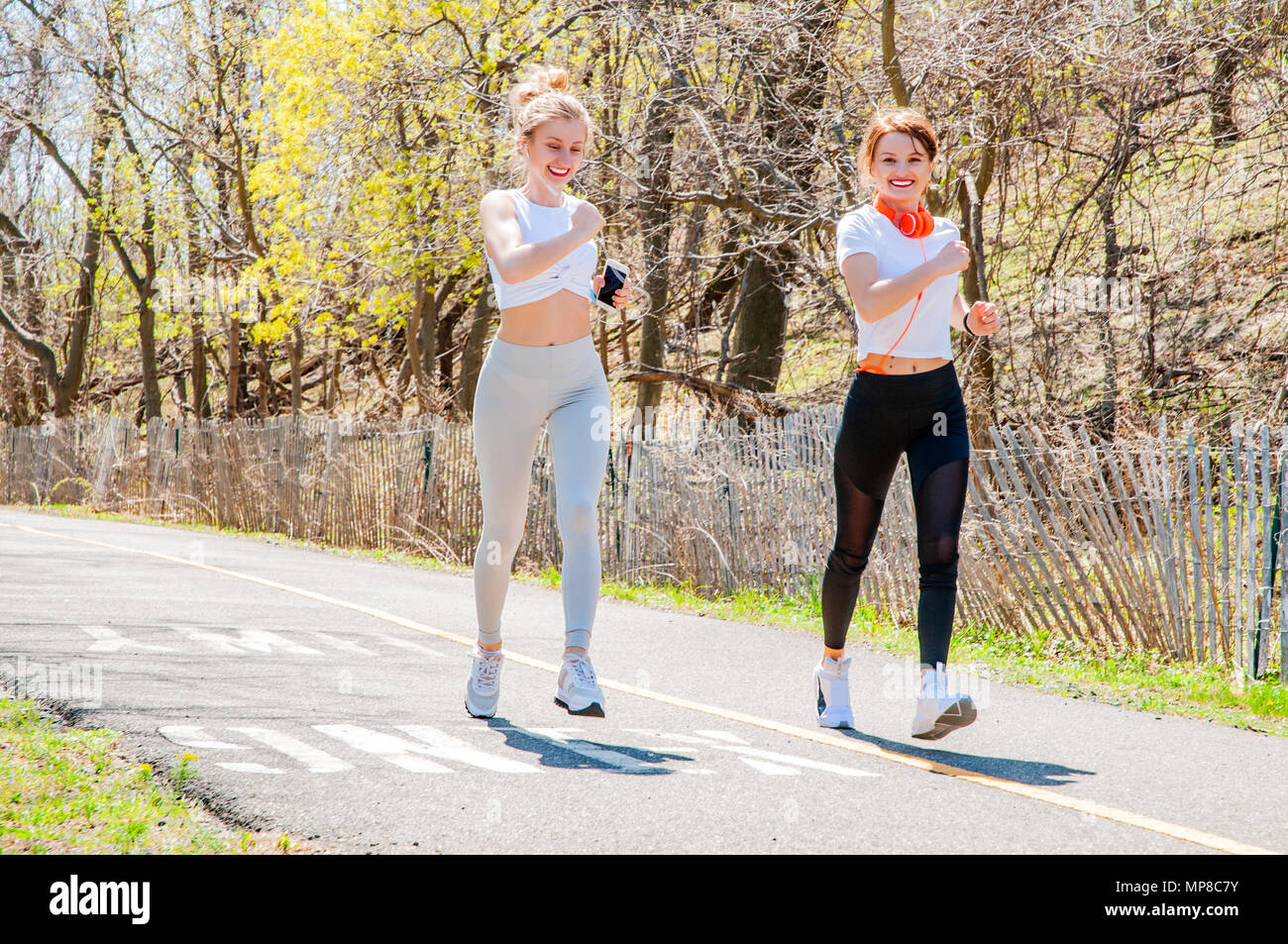 Two happy sporty girls running in the park. Female fitness training ...
