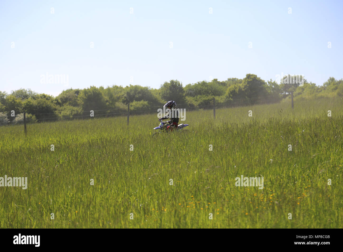 Man riding motocross motorcycle through field Stock Photo - Alamy