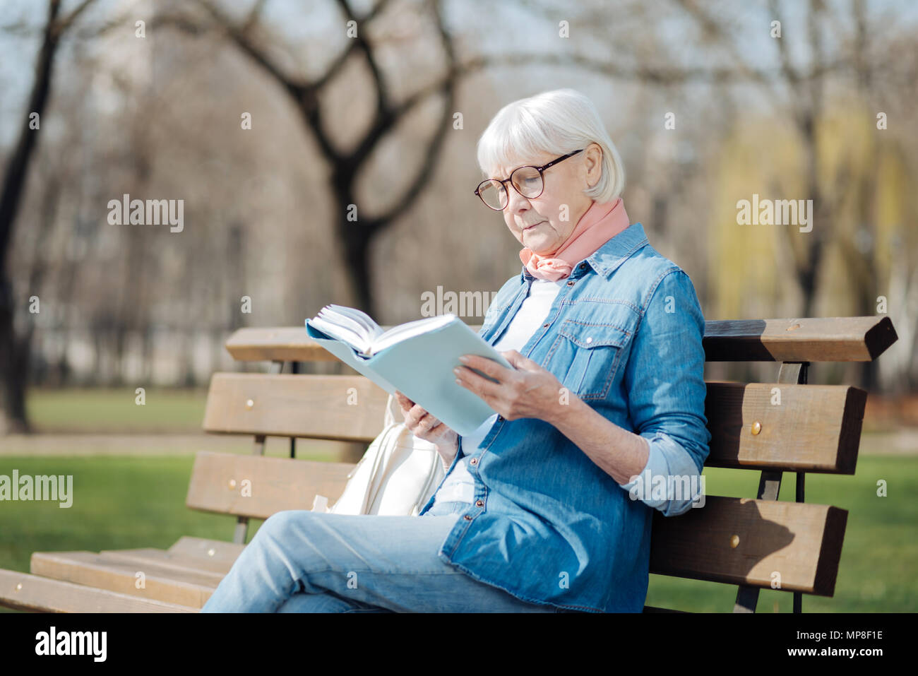Concentrated old woman reading a book Stock Photo - Alamy