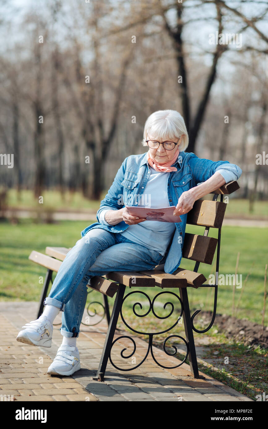 Serious old woman reading a magazine Stock Photo - Alamy