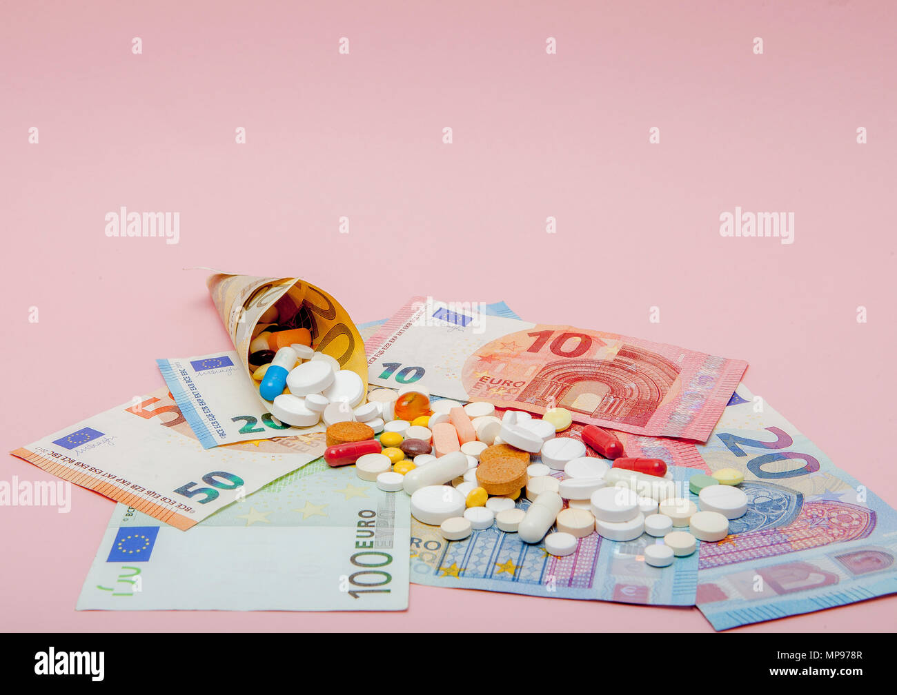 The tablets wrapped in euro with euro banknotes on a pink background ...