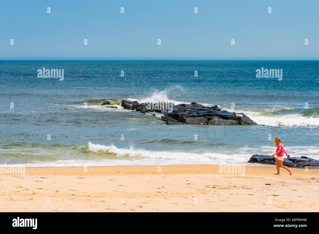Spring Lake, NJ USA -- May 20, 2018. A young woman goes for a walk on ...
