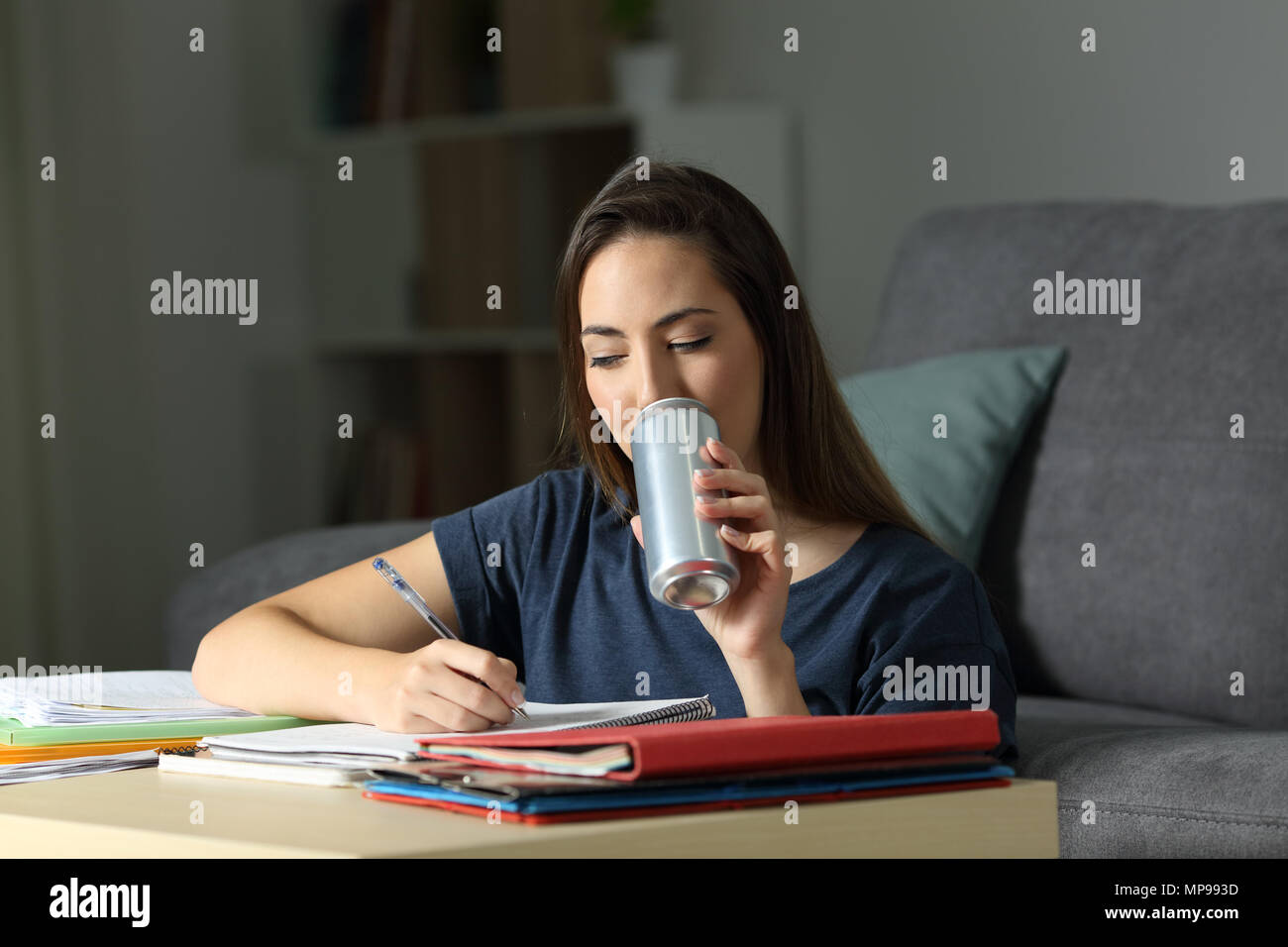 Student studying hard drinking an energy beverage at home late in the ...