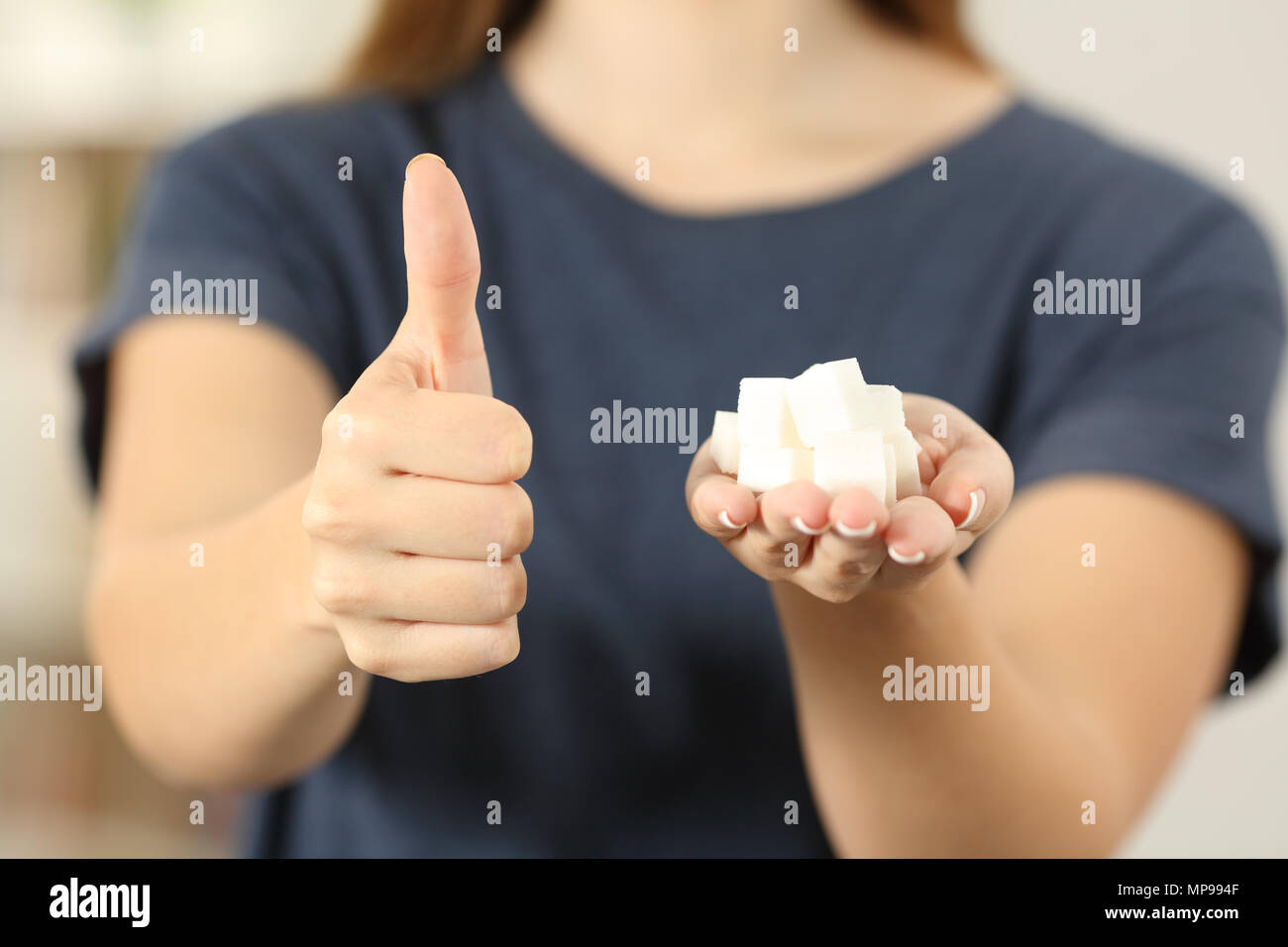 Front view close up of a woman hand holding sugar cubes with thumbs up ...