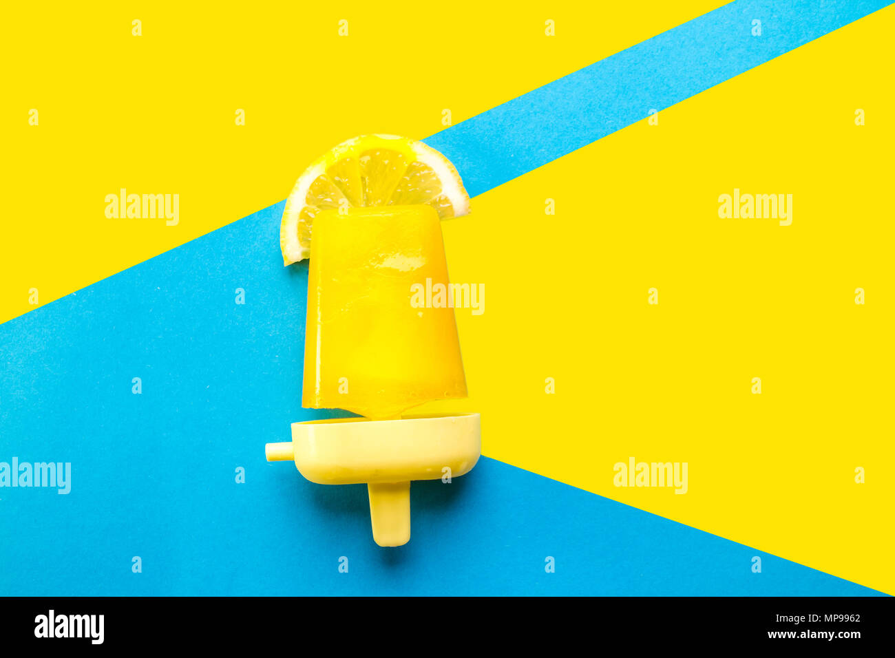 Homemade yellow lemon popsicle isolated on blue and yellow background ...
