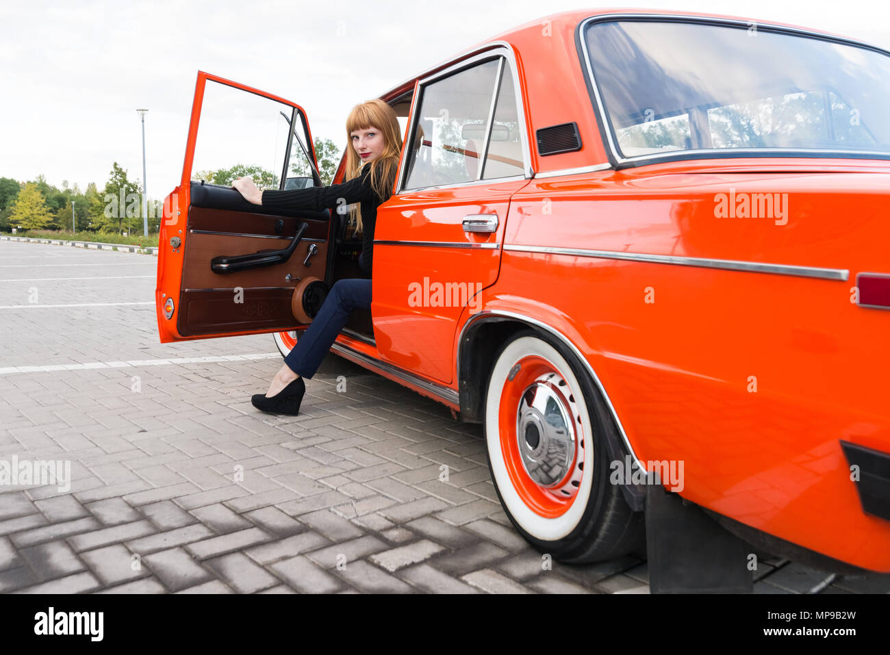 Beautiful red-haired girl coming out of the car Stock Photo - Alamy