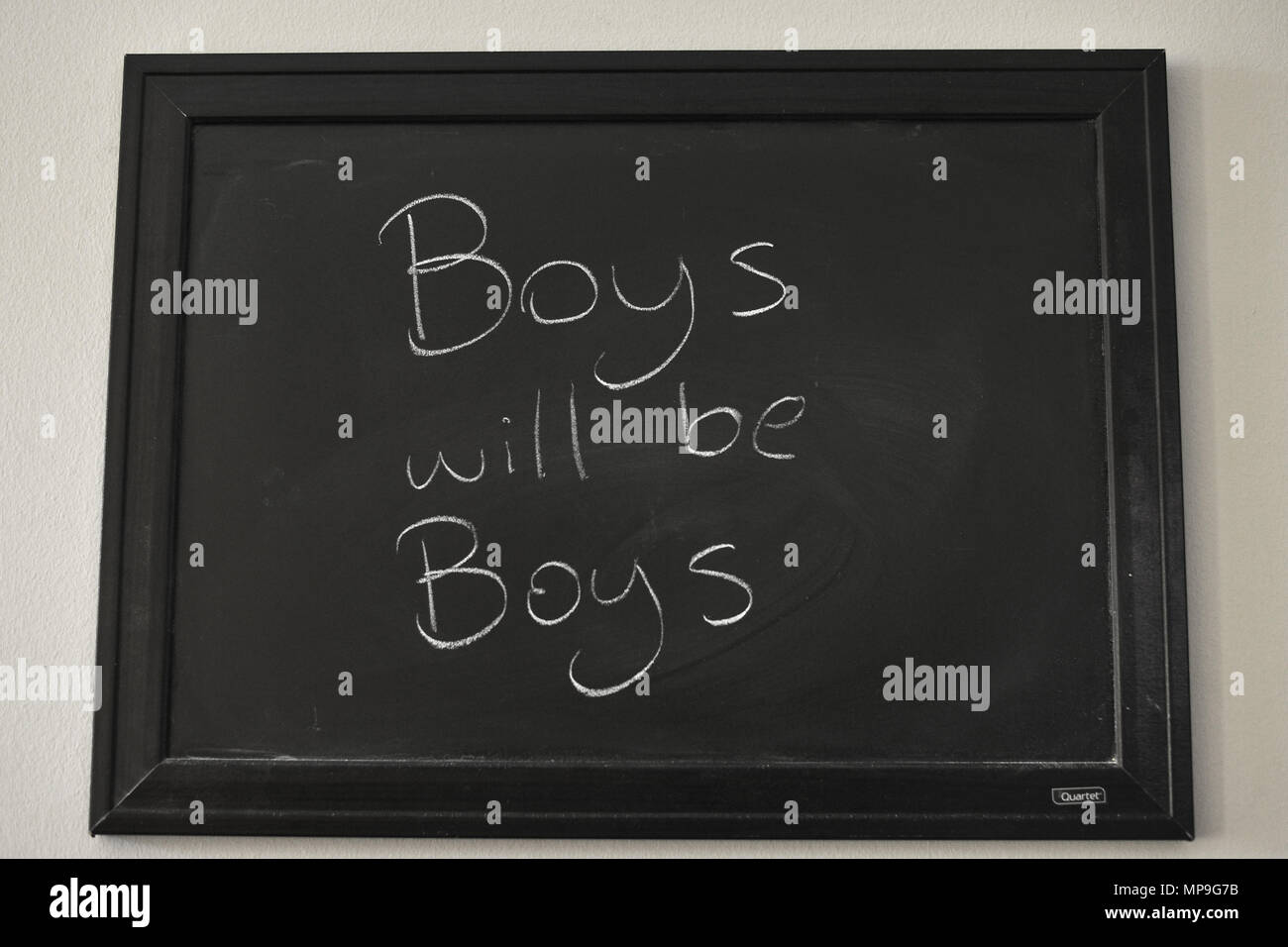 Boys will be boys written in white chalk on a wall mounted blackboard ...