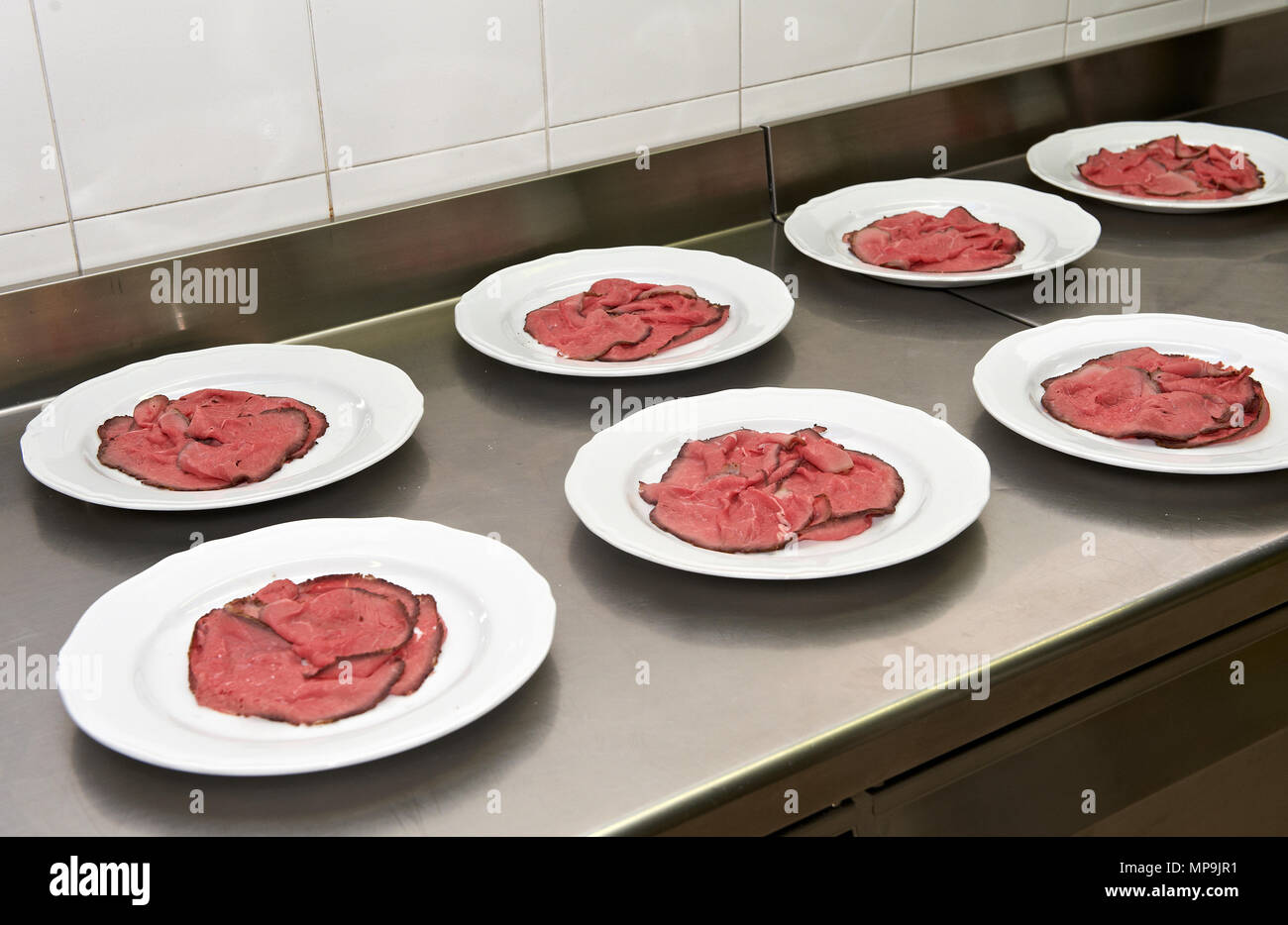 preparation of some dish with roast-beef in a kitchen of a restaurant ...