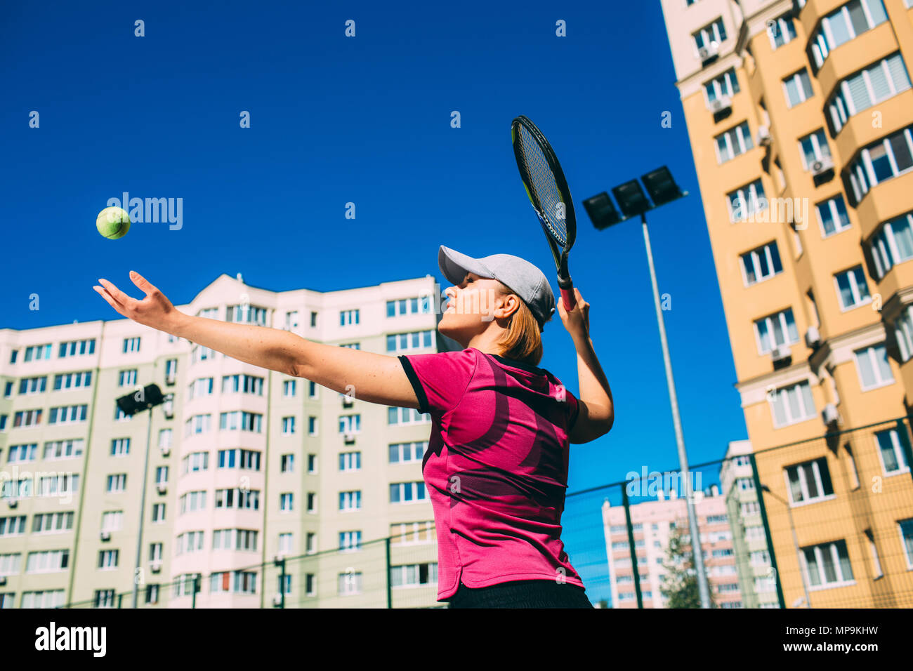 bottom view young woman, tennis player playing tennis, serving the ball ...