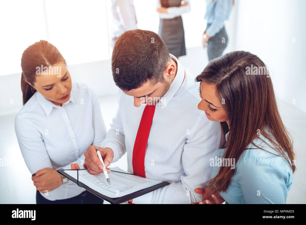 Three smiling young colleagues discussing in front their business team ...