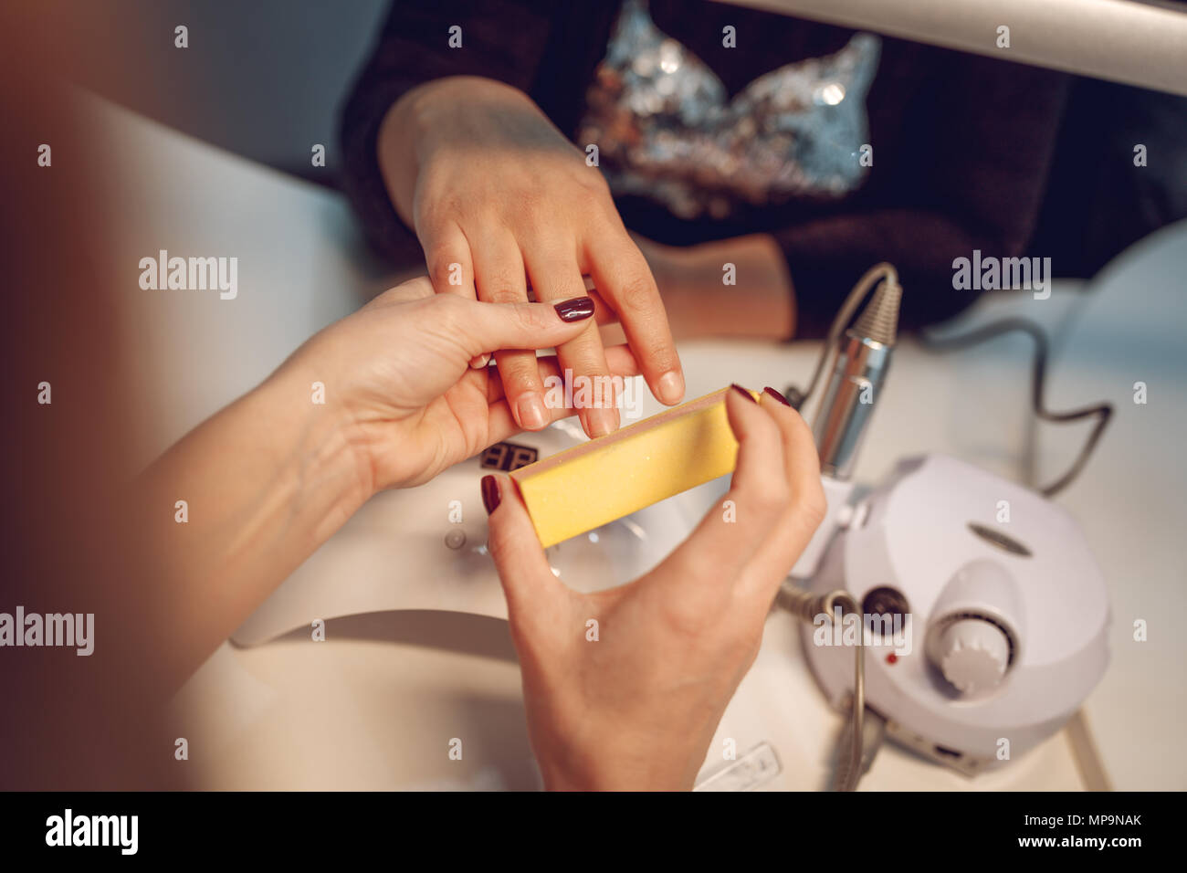 Close-up of a beautician hands polishing female clients nails with nail ...