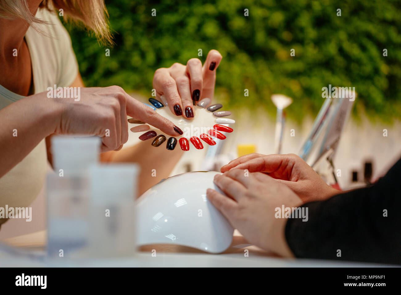 Close-up of a beautician and female clients hands holding samples and ...