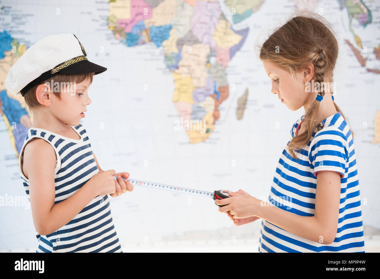 two beautiful kids in sailor striped shirts measure distance on world ...