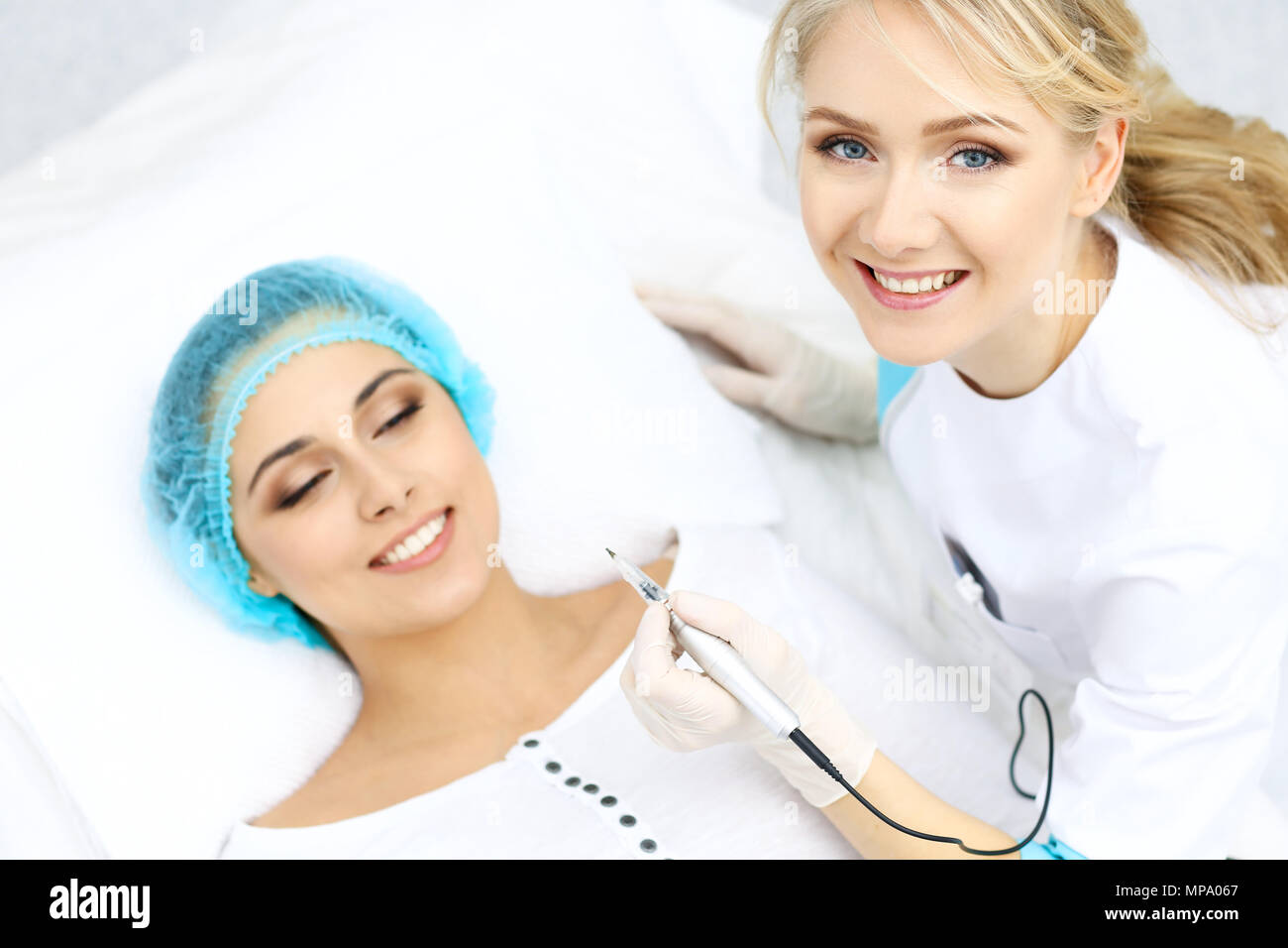 Professional beautician doing eyebrow tattoo at woman face. Permanent ...
