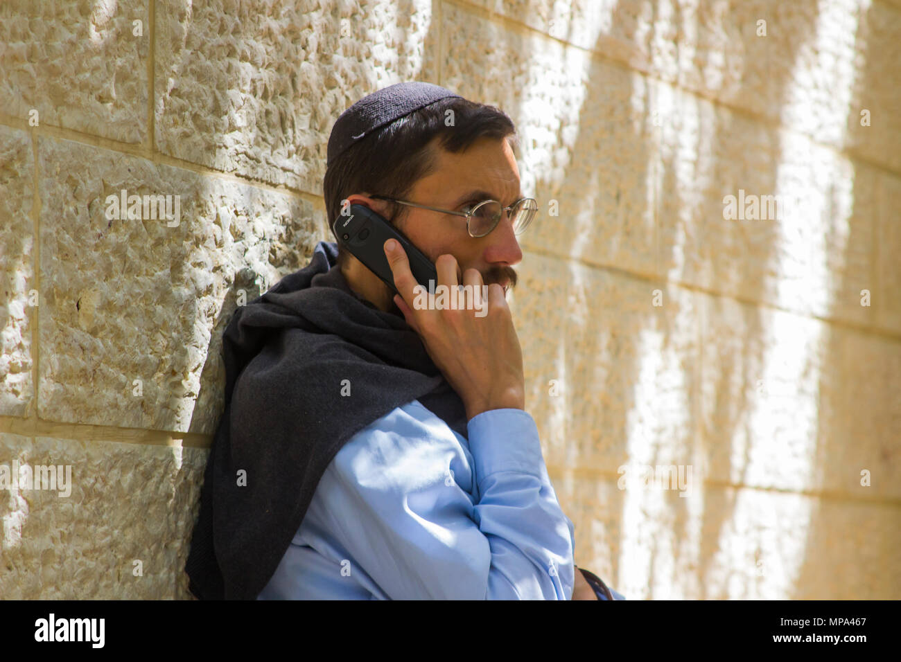 A young Jewish male with a moustache using a mobile phone while leaning ...