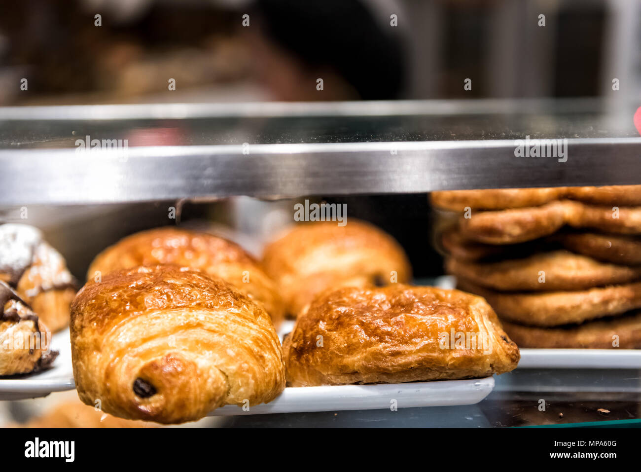 Closeup of many golden baked chocolate crisp croissants on glass shelf ...