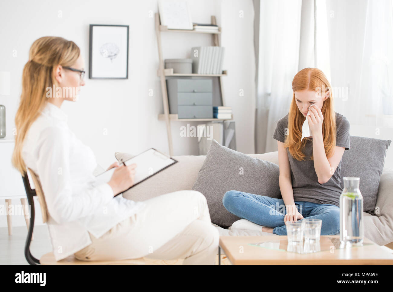 Professional psychologist counseling young depressed woman crying in ...