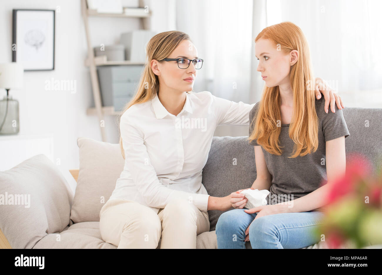 Female therapist comforting young patient in her office at ...