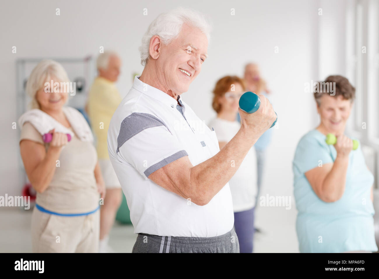 Older man exercising biceps using dumbbell during fitness classes Stock ...