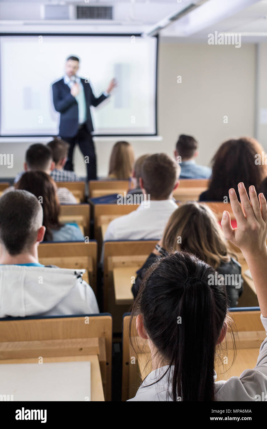 Woman back view raising hand during conference in lecture hall Stock ...