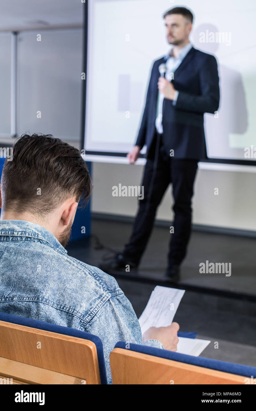 Young man in suit standing in lecture hall Stock Photo - Alamy