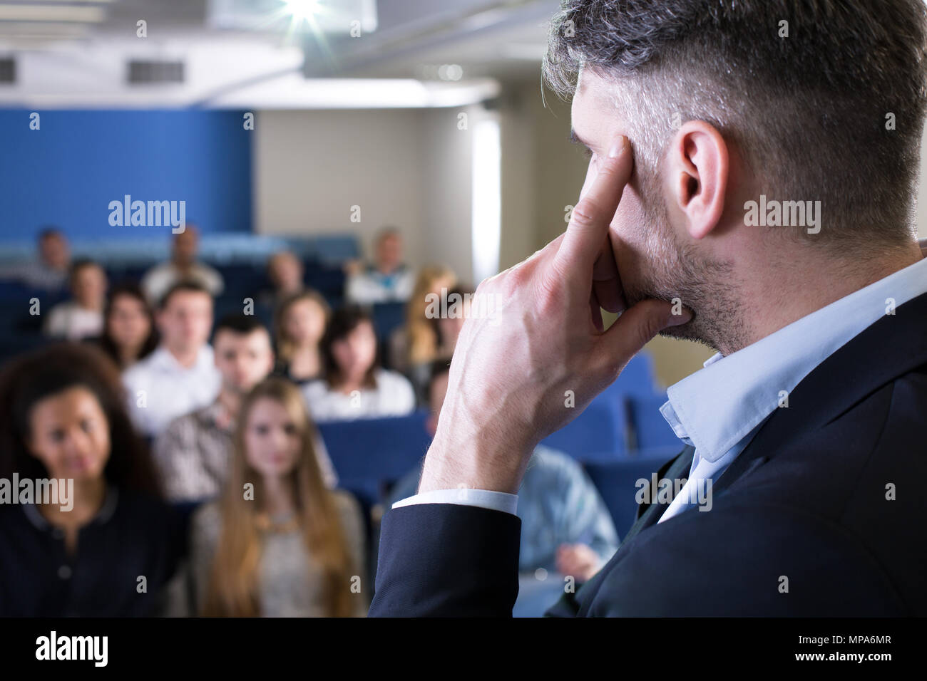 Young man in suit back view sitting in lecture hall with a group of ...