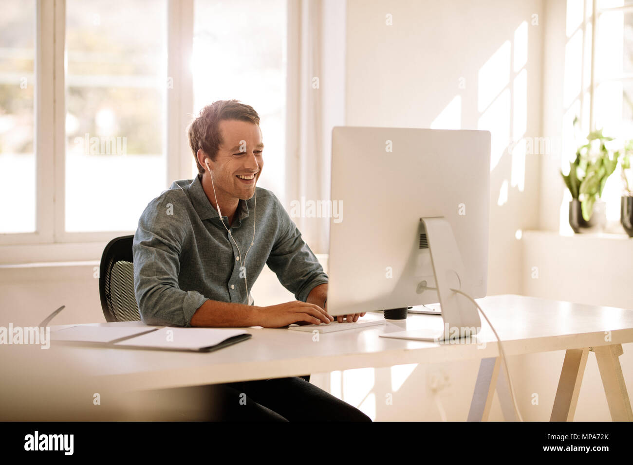Smiling businessman working on computer. Man sitting at his work table ...