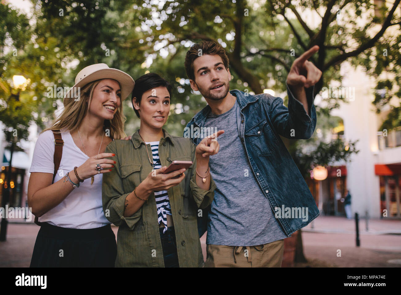 Group of friends on city tour using mobile phone for navigation. Three ...