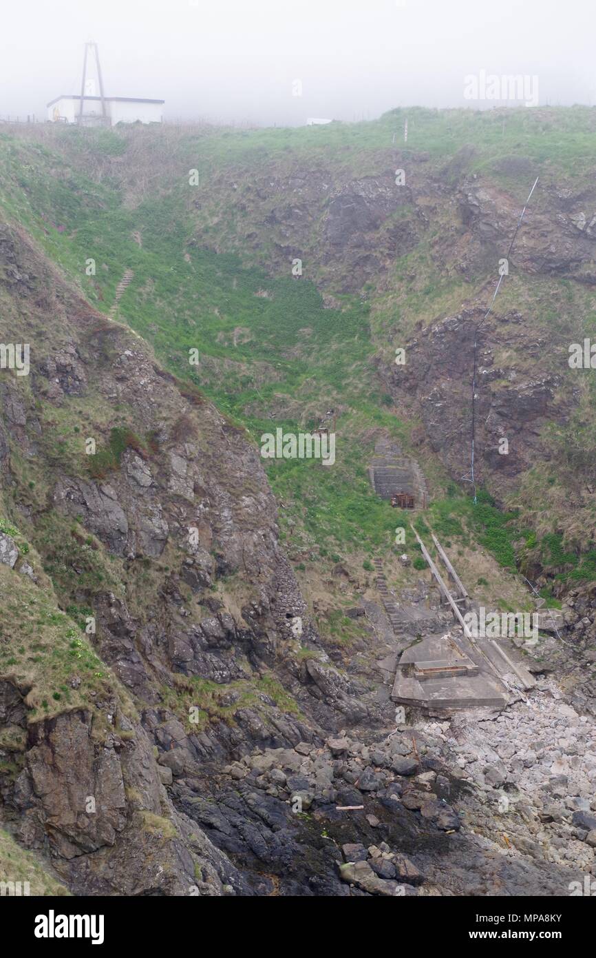 Old Boat Winch Down a Rugged Grassy Coastal Cliff Under Thick Sea Fog ...