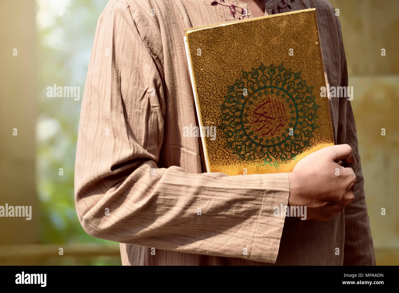 Muslim man holding Quran on the mosque Stock Photo - Alamy