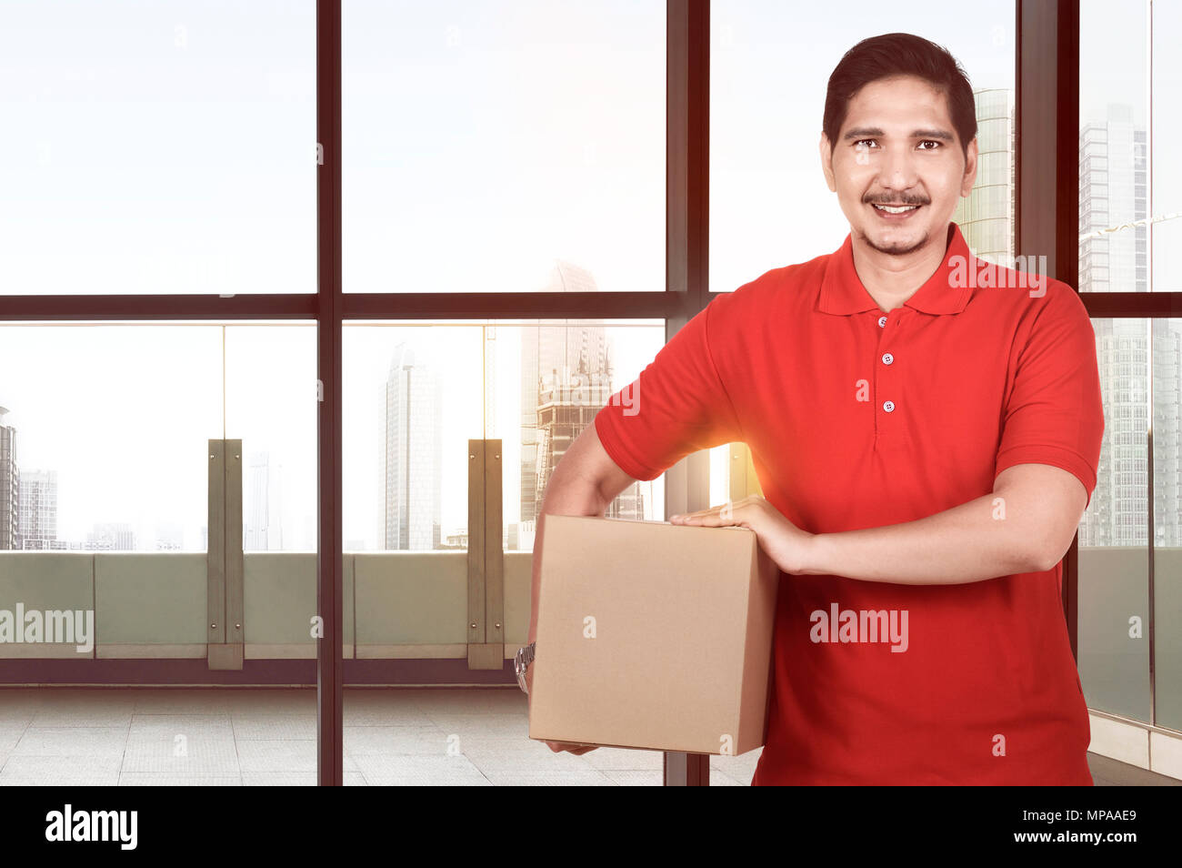 Attractive asian delivery man carrying package on the office Stock ...
