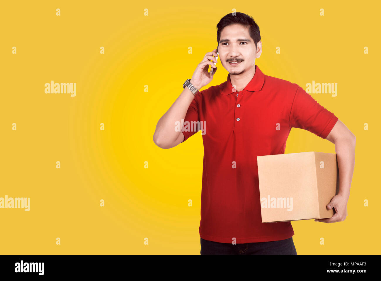 Professional asian delivery man using phone while carrying parcel over ...