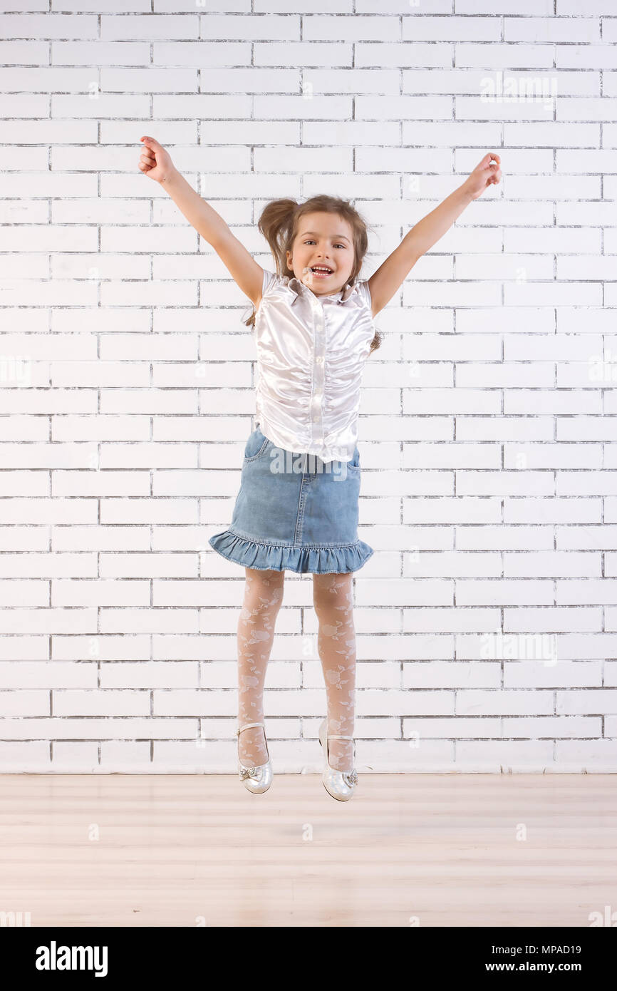 little girl in a jump near the white brick wall Stock Photo - Alamy