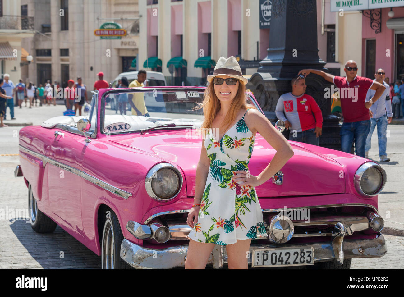 Tourist woman posing for photo with classic pink Ford car in Old Havana ...