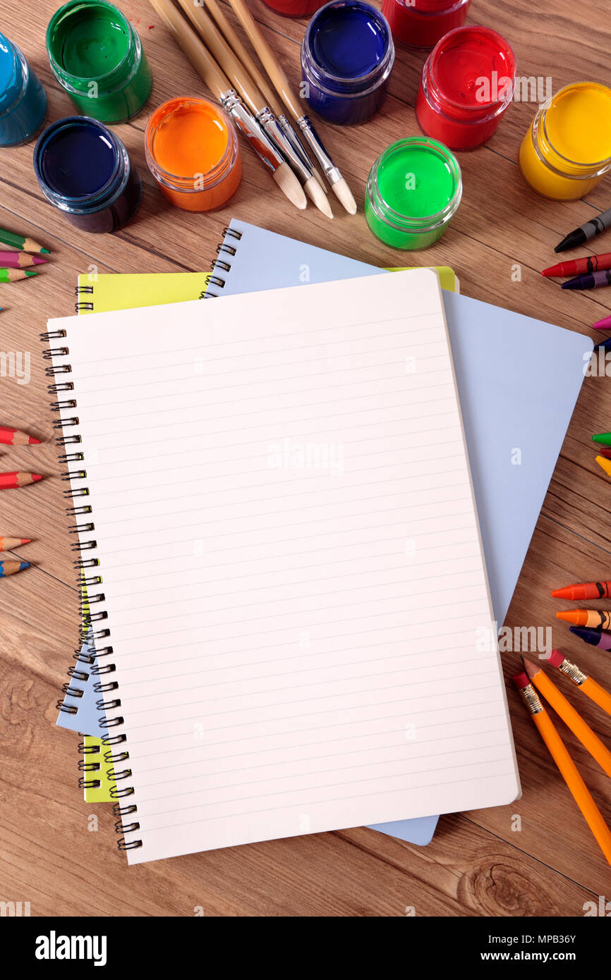 Blank white open notebook on a school desk with various paints, pencils ...