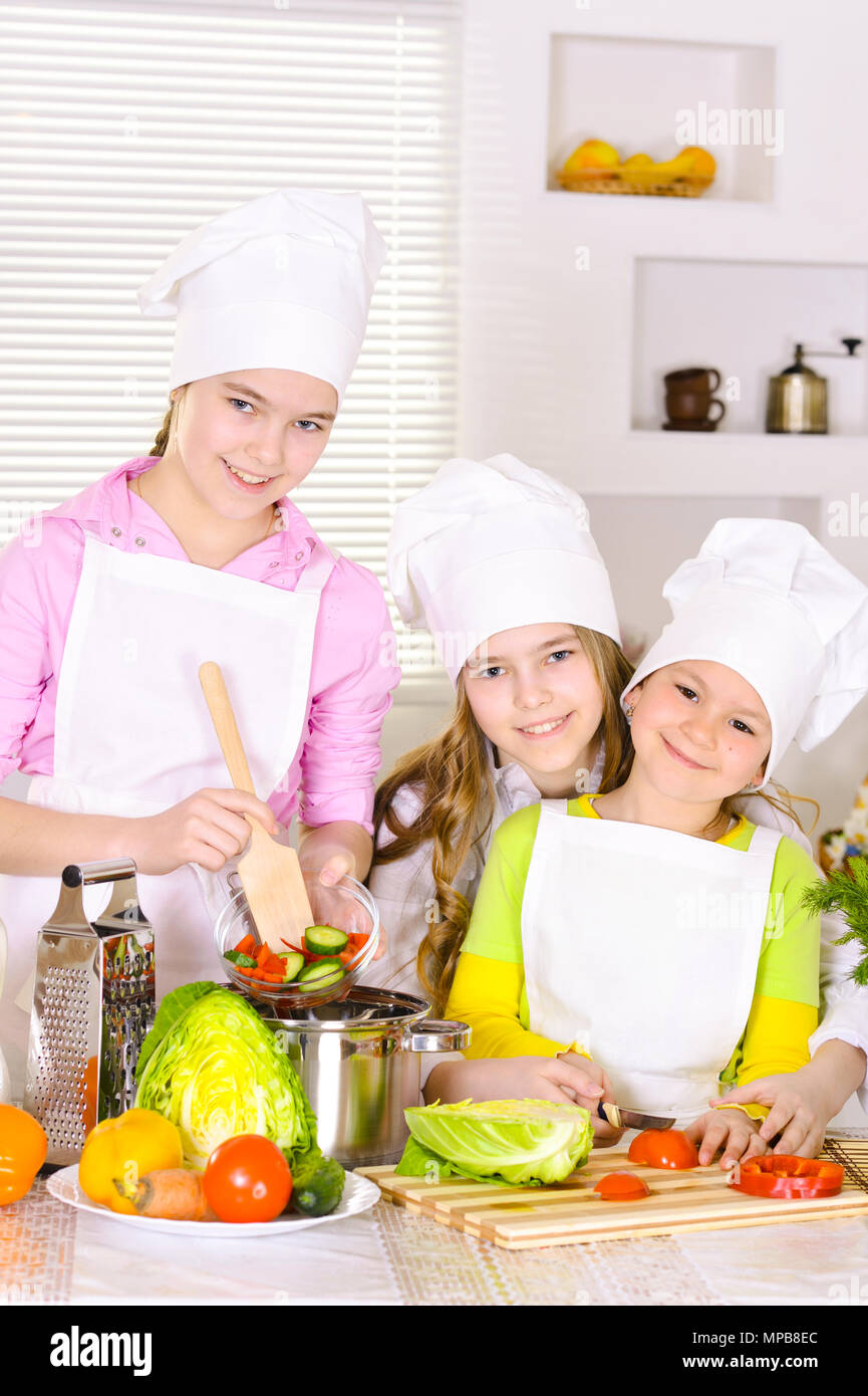 happy cute girls cooking vegetable dish on kitchen Stock Photo - Alamy
