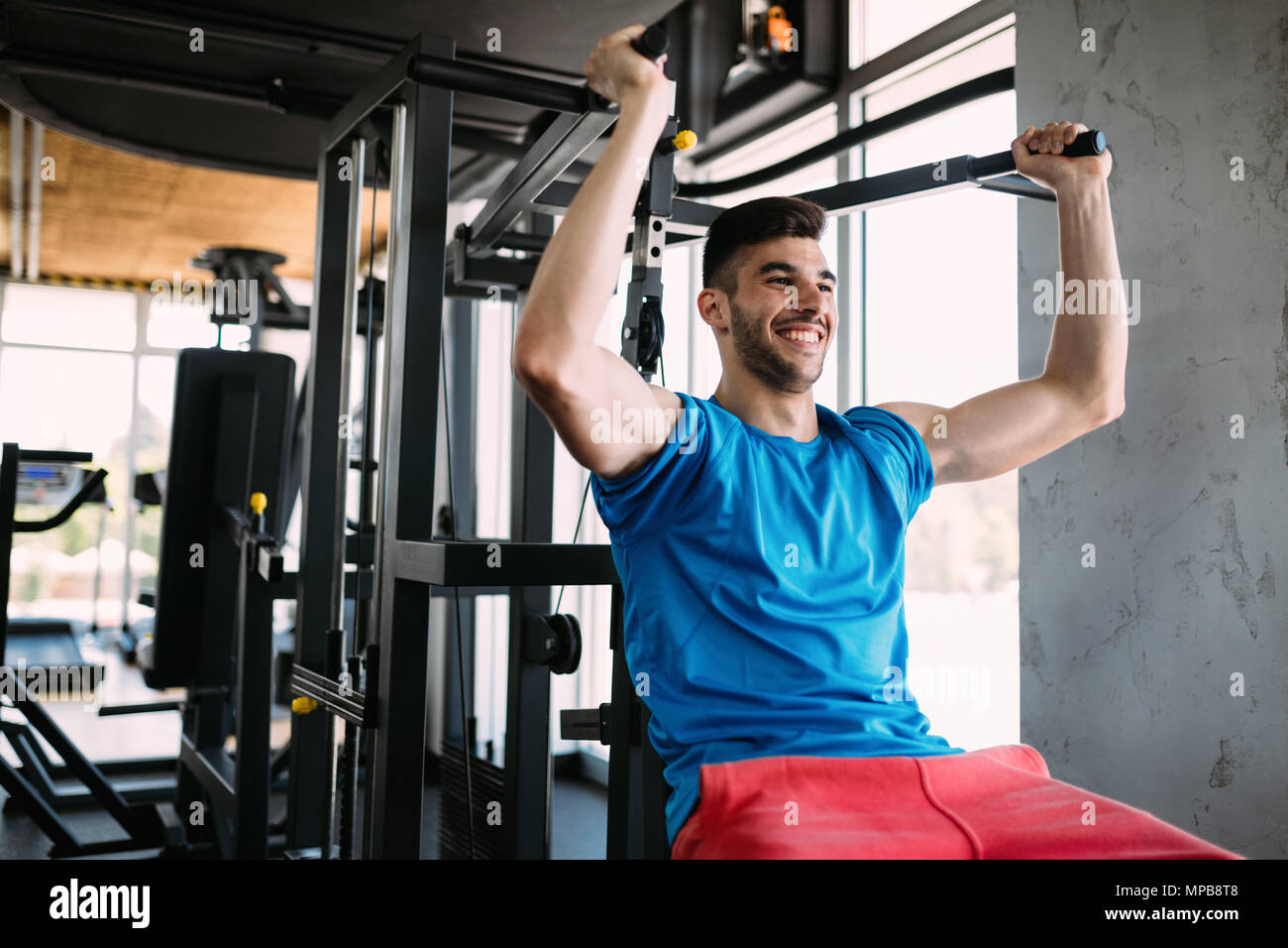 Fit man exercising at the gym on a machine Stock Photo - Alamy