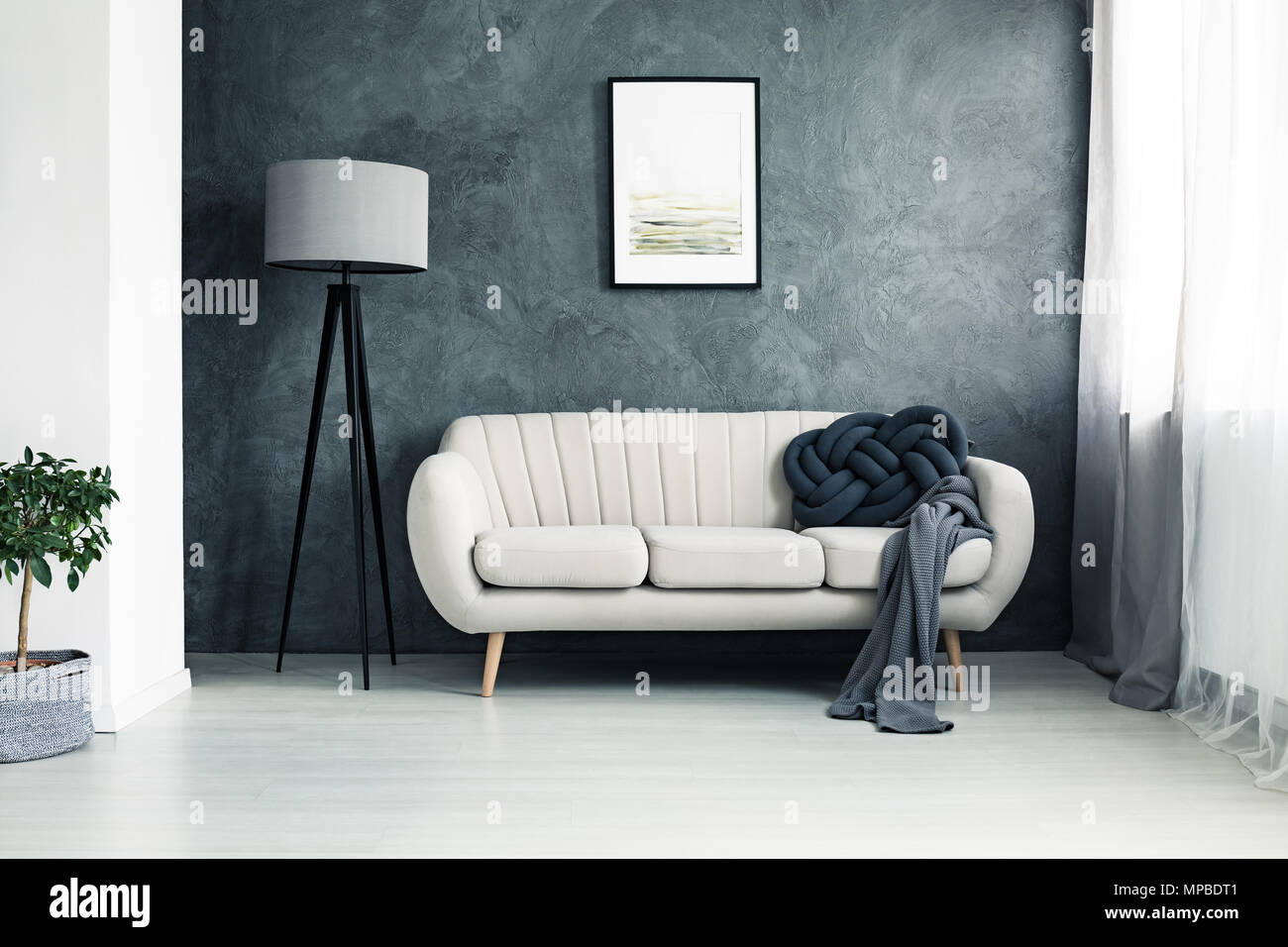 Bright couch with handmade knot cushion and grey blanket standing in a ...