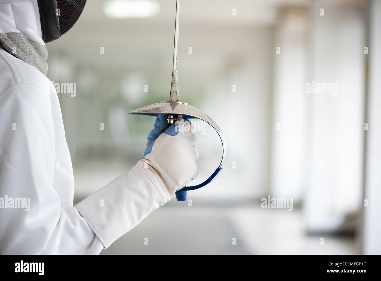 Close-up of a fencer in white fencing suit and holding her sword. Sport and recreation concept ...