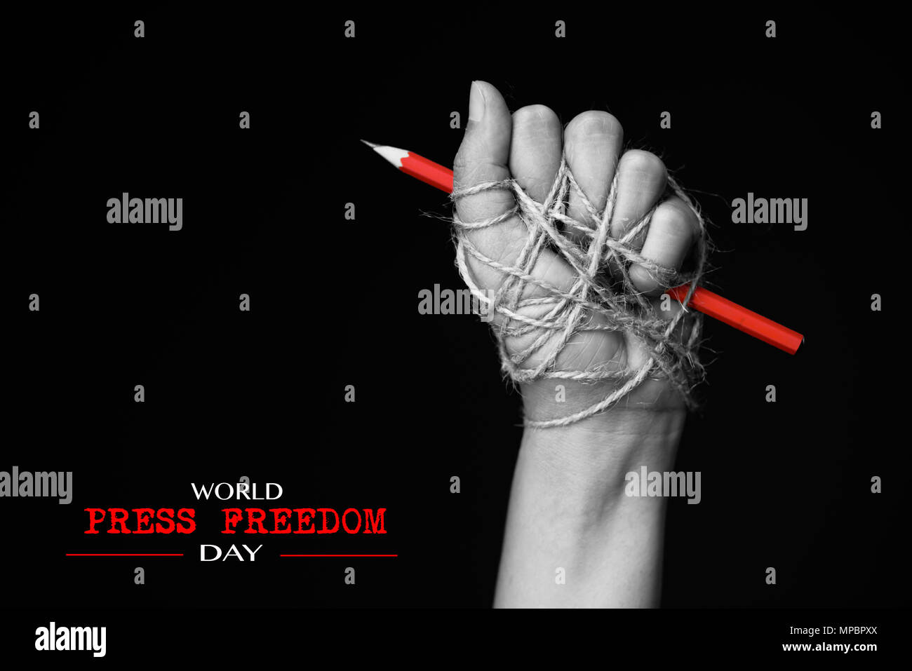 Hand with red pencil tied with rope, depicting the idea of freedom of ...