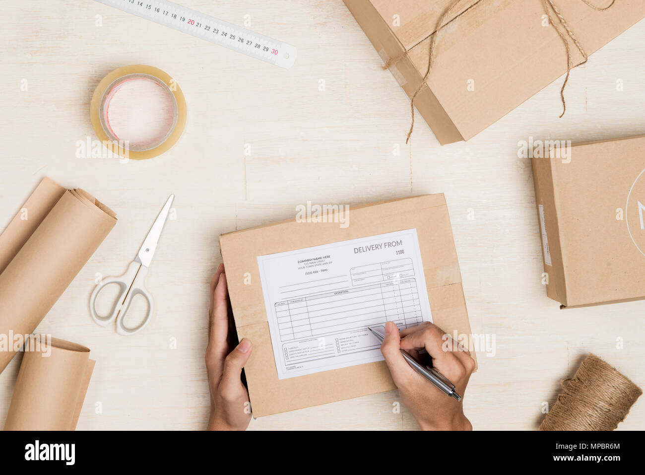 Top view of making notes in delivery receipt among parcels at table ...