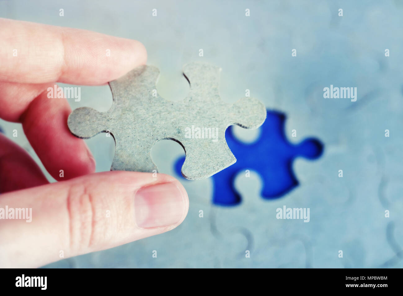 Hand holding piece of puzzle with the last missing piece. Business ...