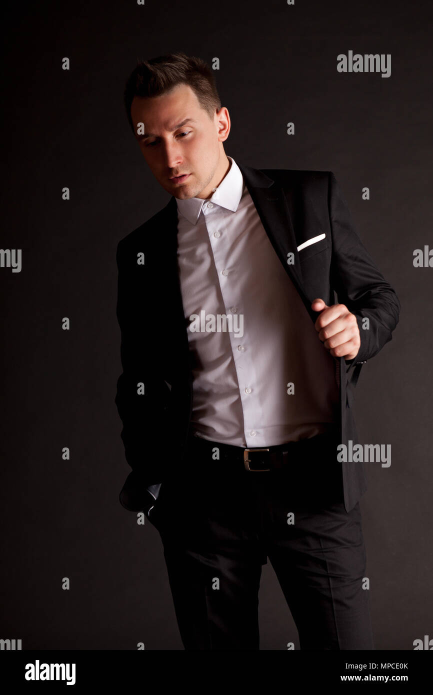 A confident elegant handsome young man standing in front of a black ...