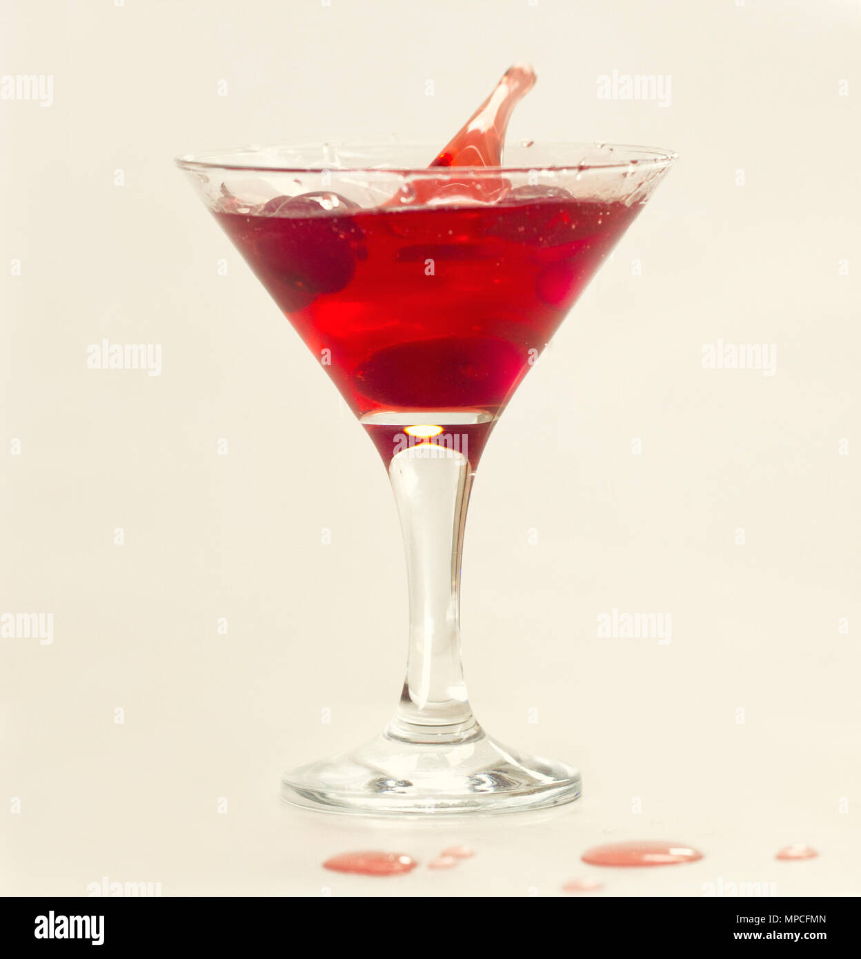 Drop of water falling in martini glass in purple tones Stock Photo - Alamy