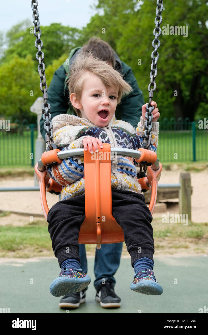 Father pushing his 18 month old son on a playground swing Stock Photo ...