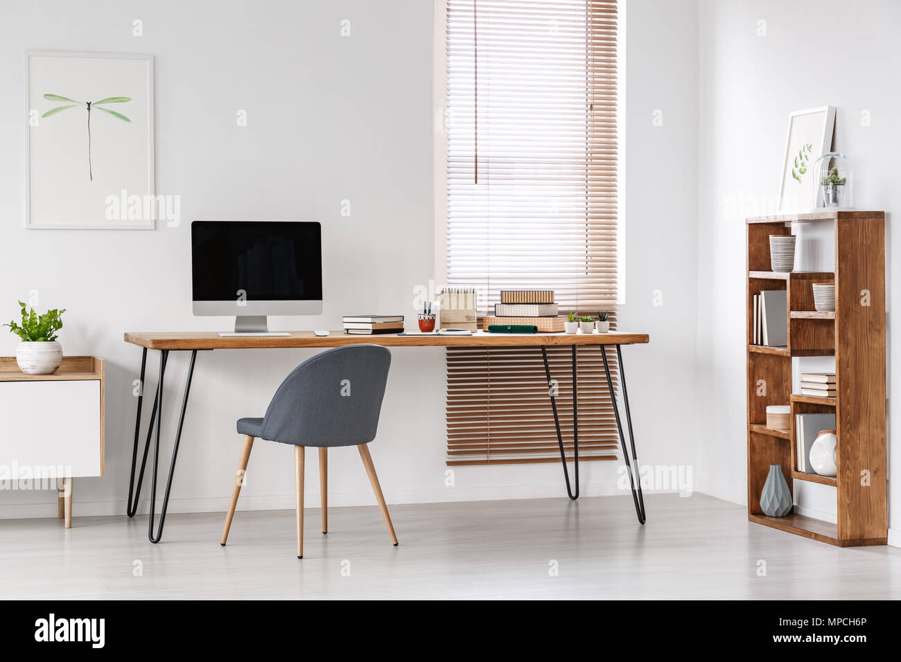 Grey chair at desk with computer monitor in minimal workspace interior ...