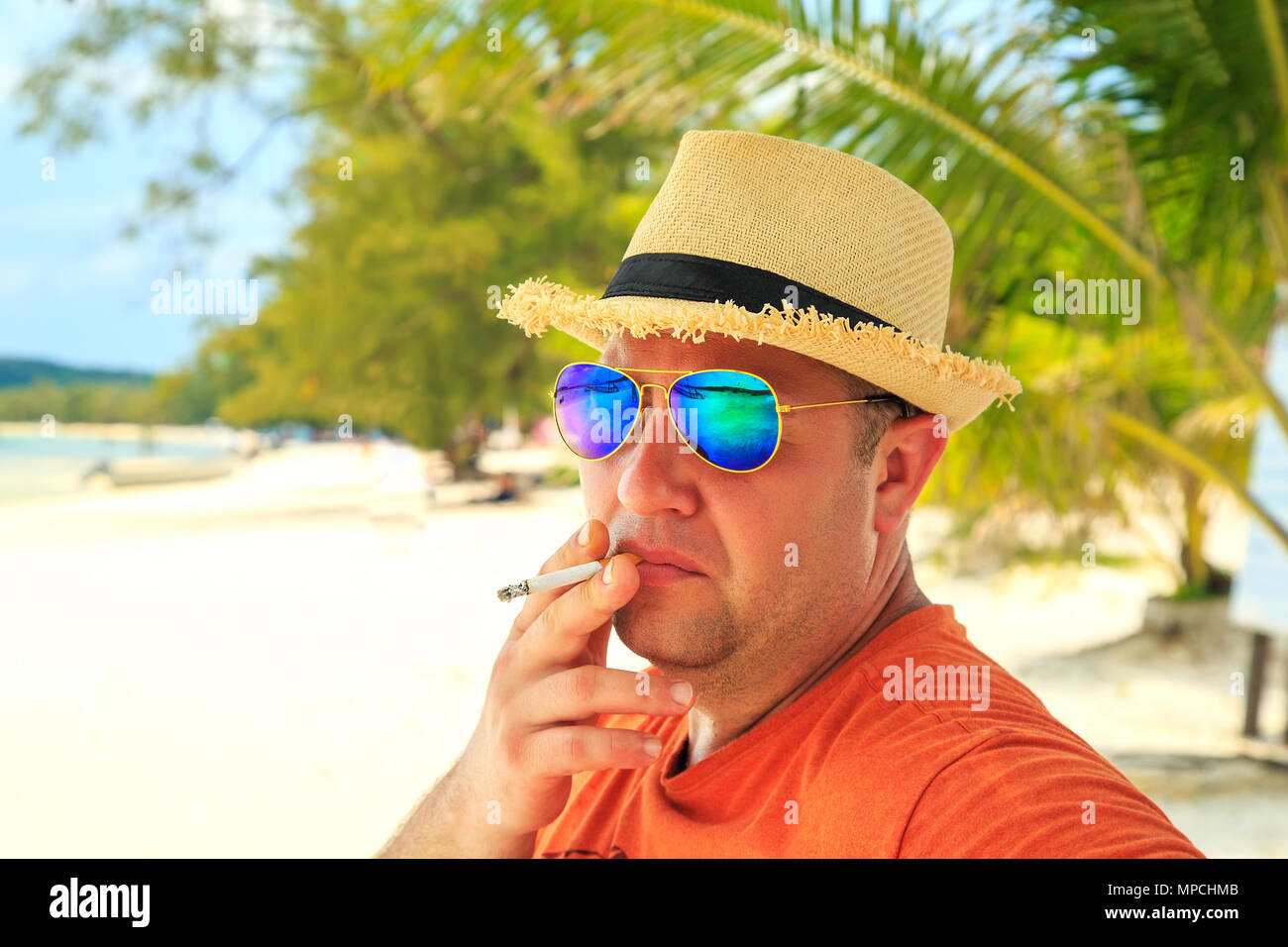 Tourist in sunglasses and hat smoking on the beach Stock Photo - Alamy