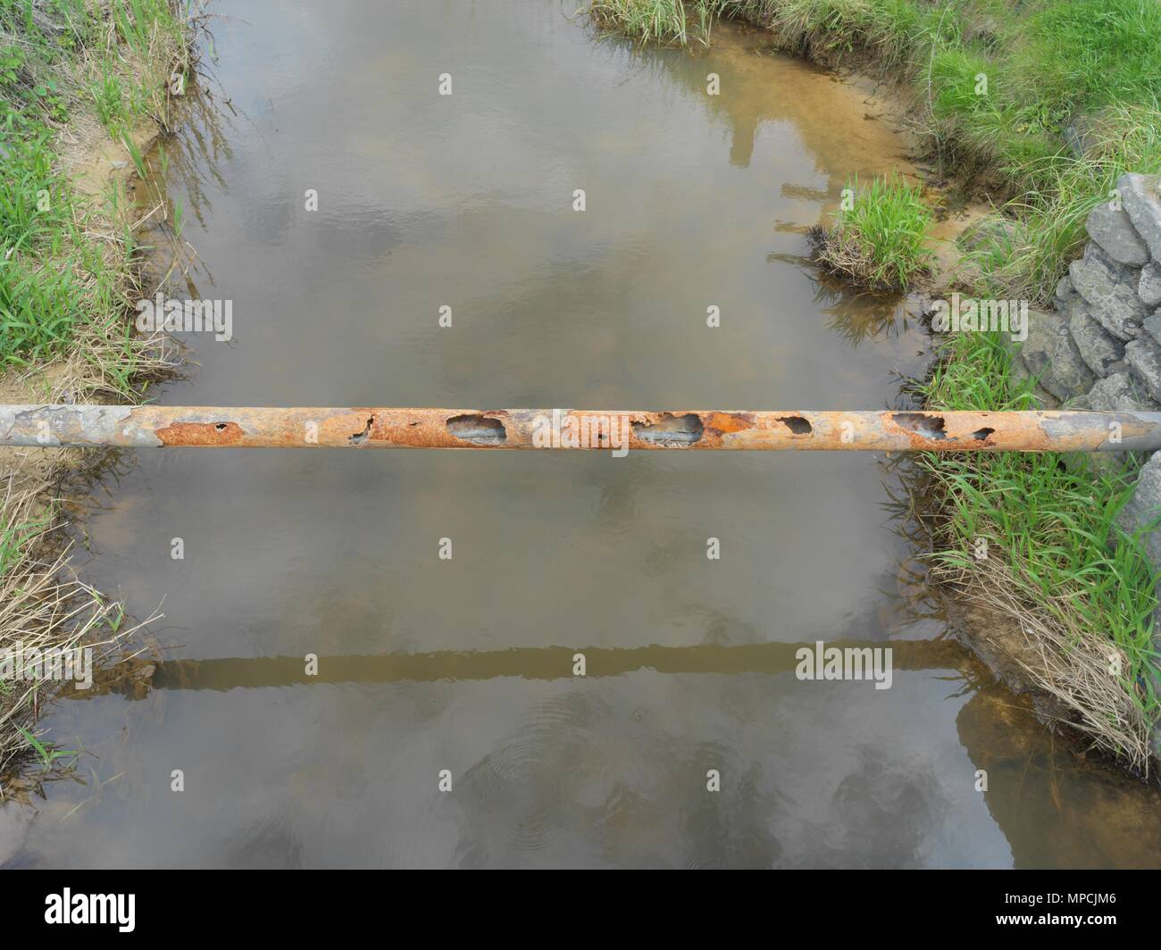 A cable (or plastic pipe?) crossing a stream inside a rusty and ...