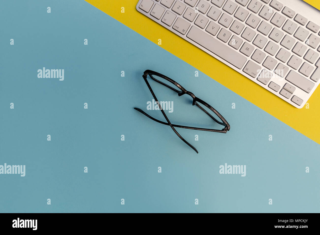 Computer keyboard eyeglasses on bright yellow blue background Stock ...