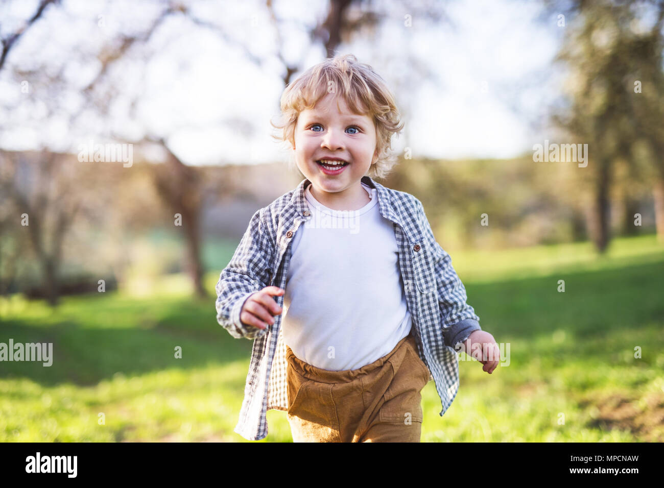 Happy toddler boy running outside in spring nature Stock Photo - Alamy